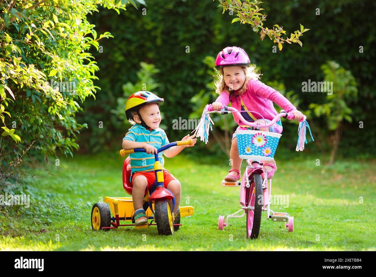 Kids riding bikes in a park. Children enjoy bike ride in the garden ...