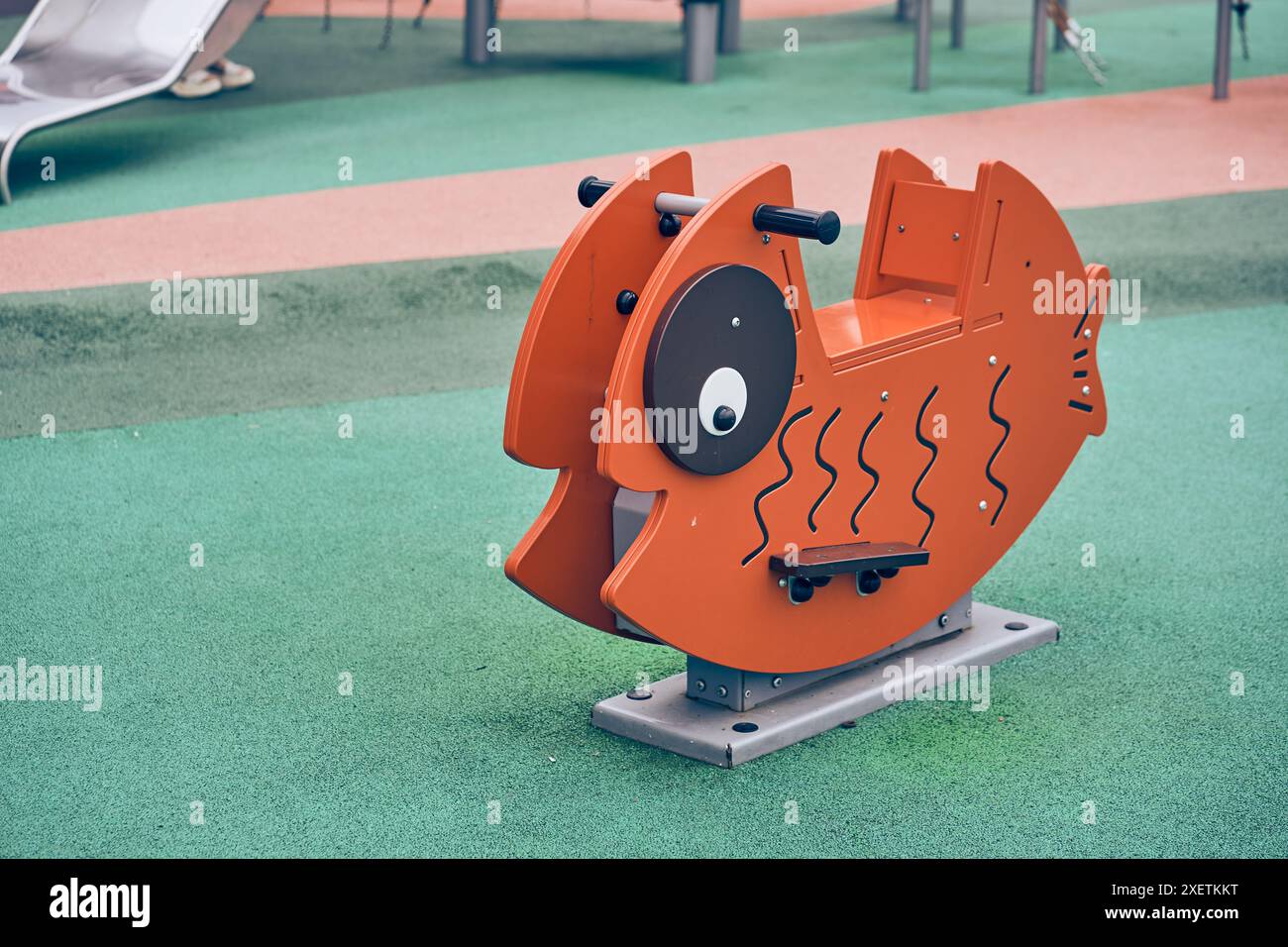 A swing in the form of a fish on the playground in the park. Covering ...