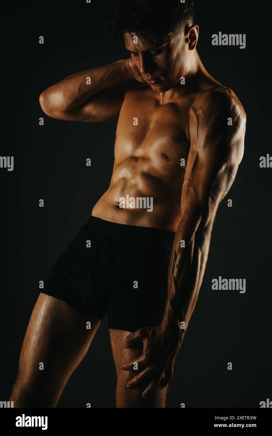 Fit man showing his abs in low-light studio setting Stock Photo - Alamy