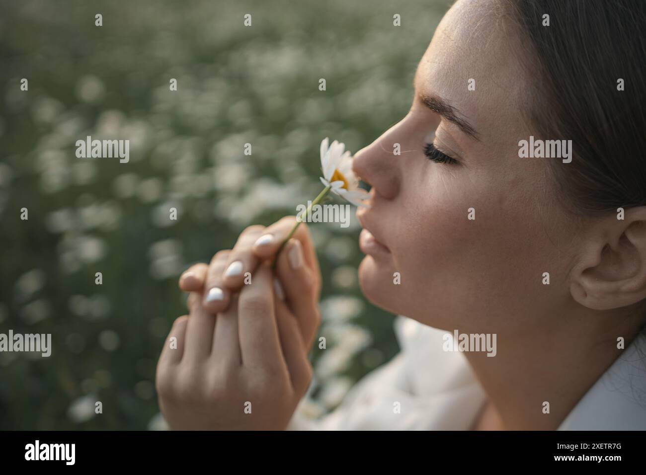 A woman is holding a flower and smelling it. Concept of peace and ...