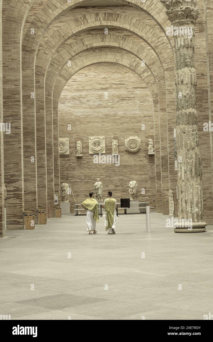 wo visitors dressed in Roman attire walk through the grand hall of the ...