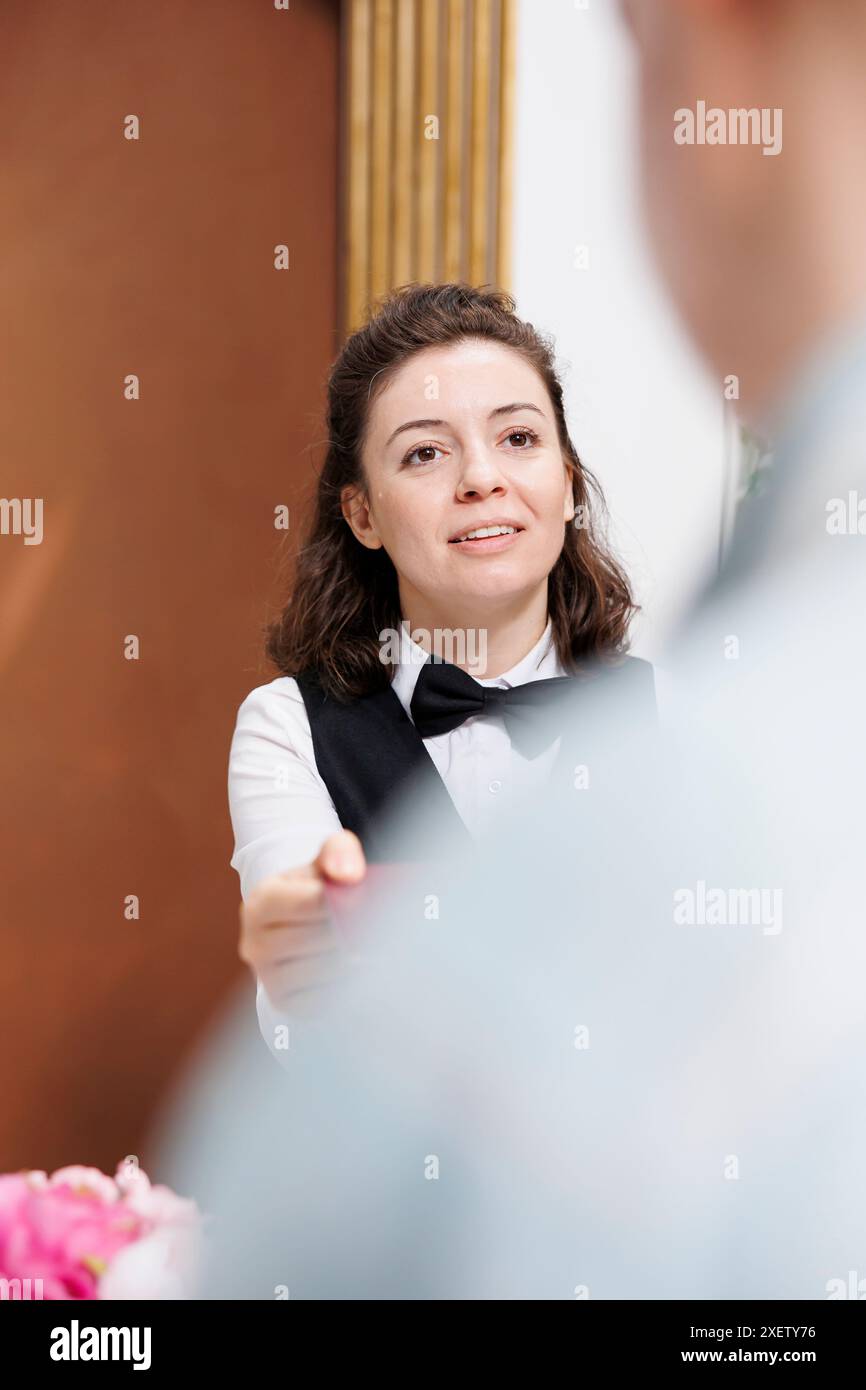 Photo focus on female receptionist helping elderly man at front desk ...