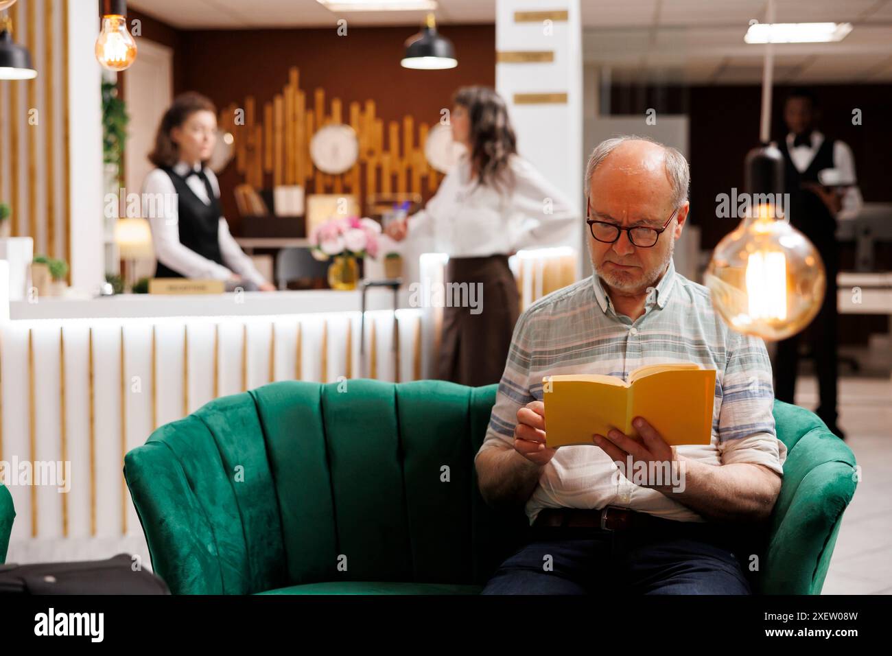 With assistance from receptionist in hotel lobby, retired senior woman ...