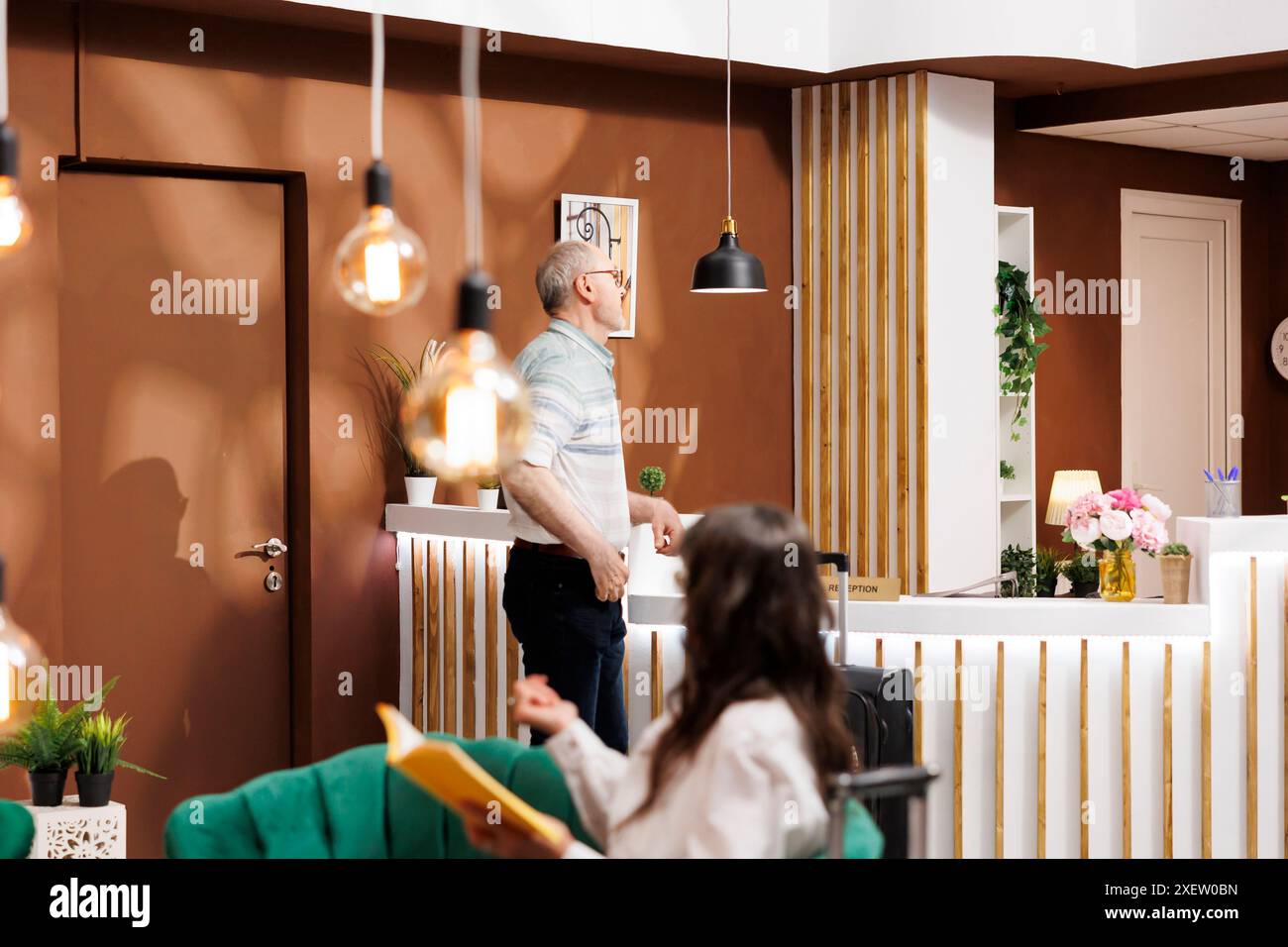 Caucasian old man standing and lingering at front desk of modern hotel ...