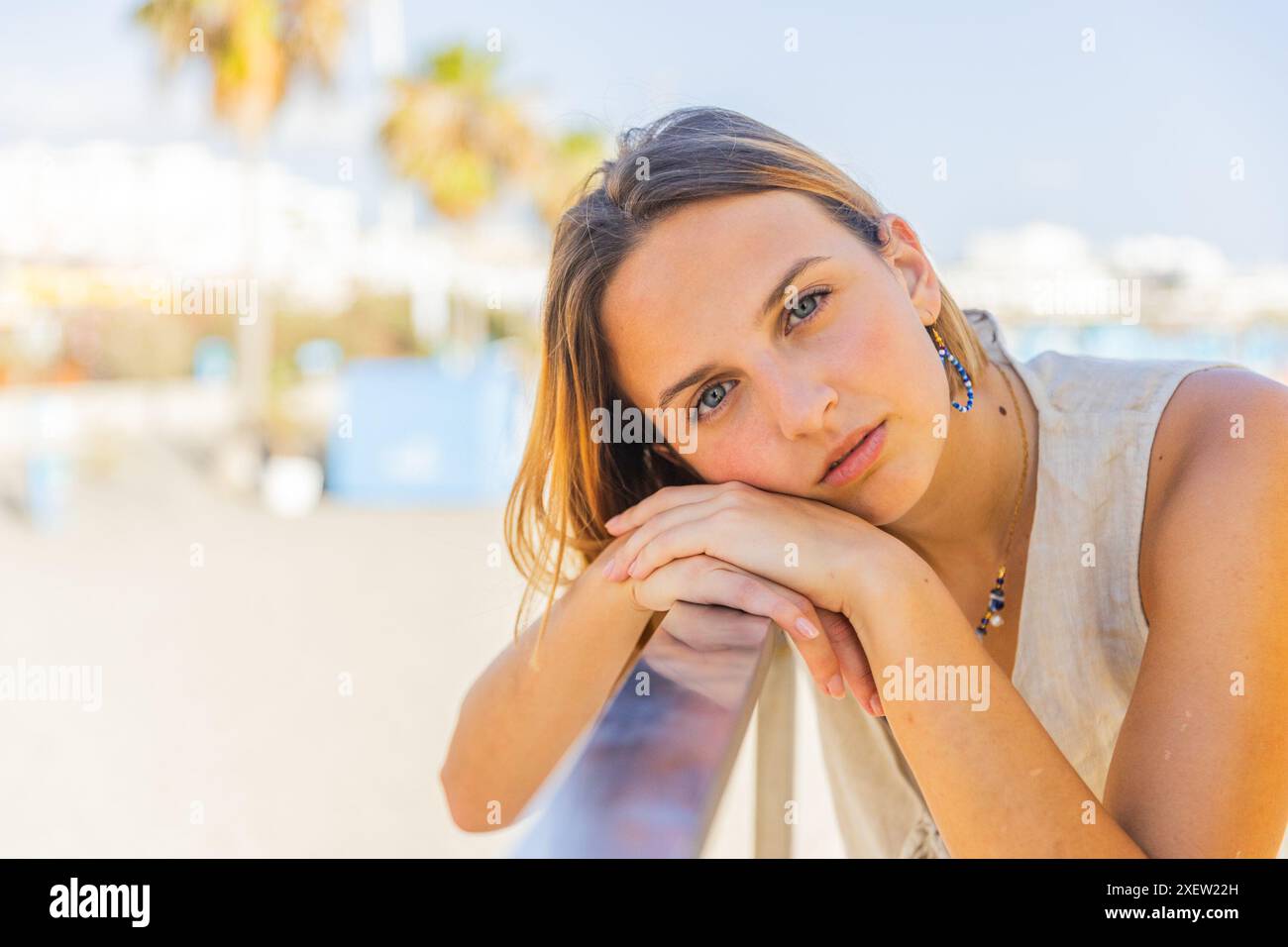 A woman is leaning against a railing with her head down, serious facial ...
