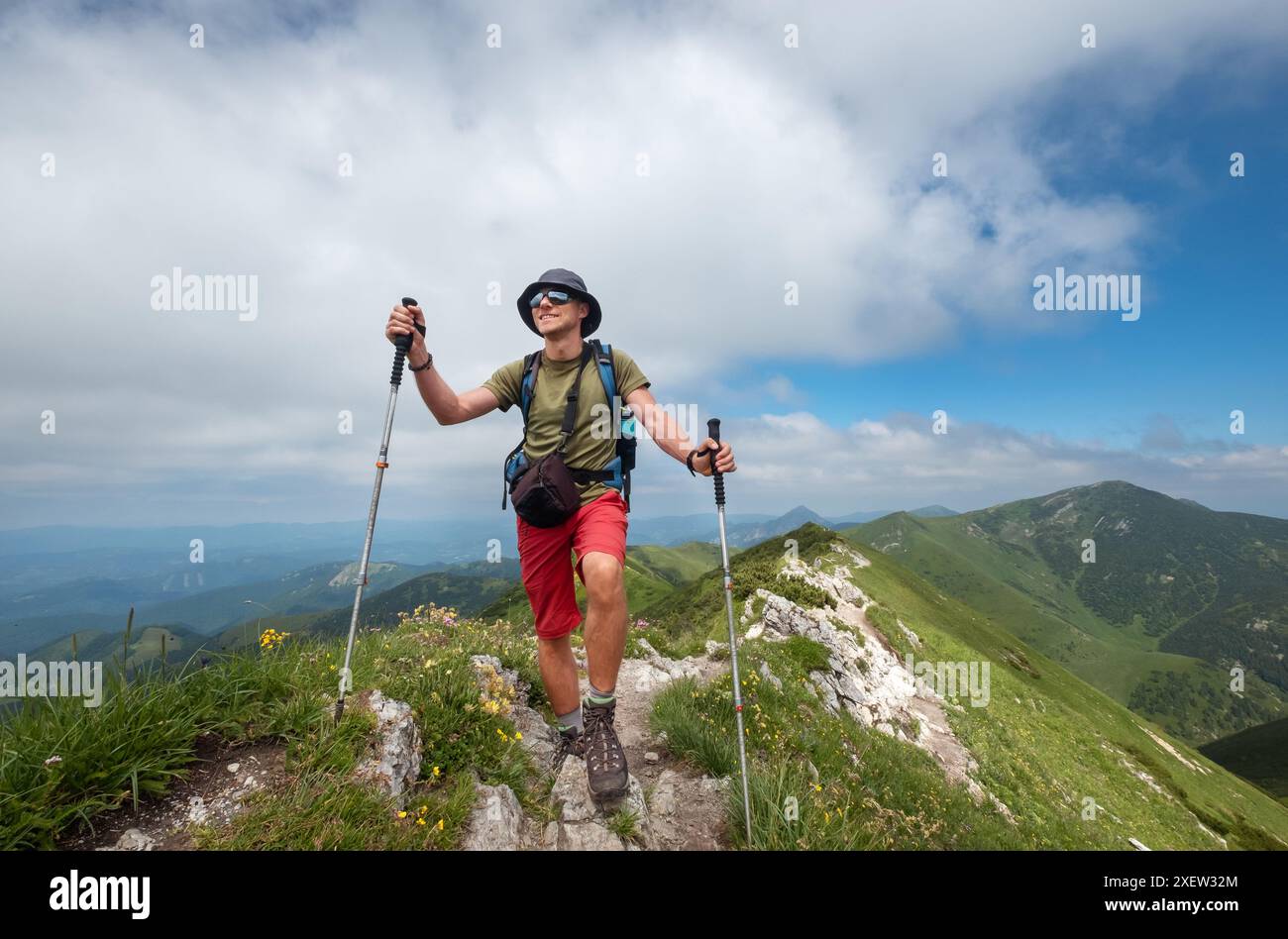 Hiker with trekking poles, backpack navigates rocky mountain trail on ...