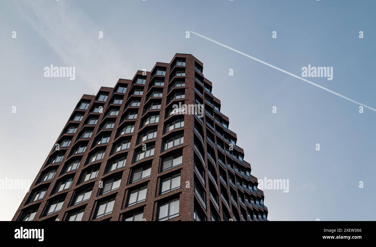 A trace of a passing plane over a modern multi-storey business class ...
