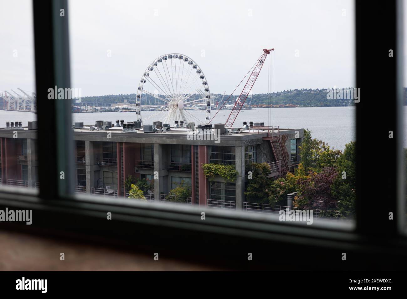 Seattle waterfront with ferris wheel, port cranes, and ferry in view ...