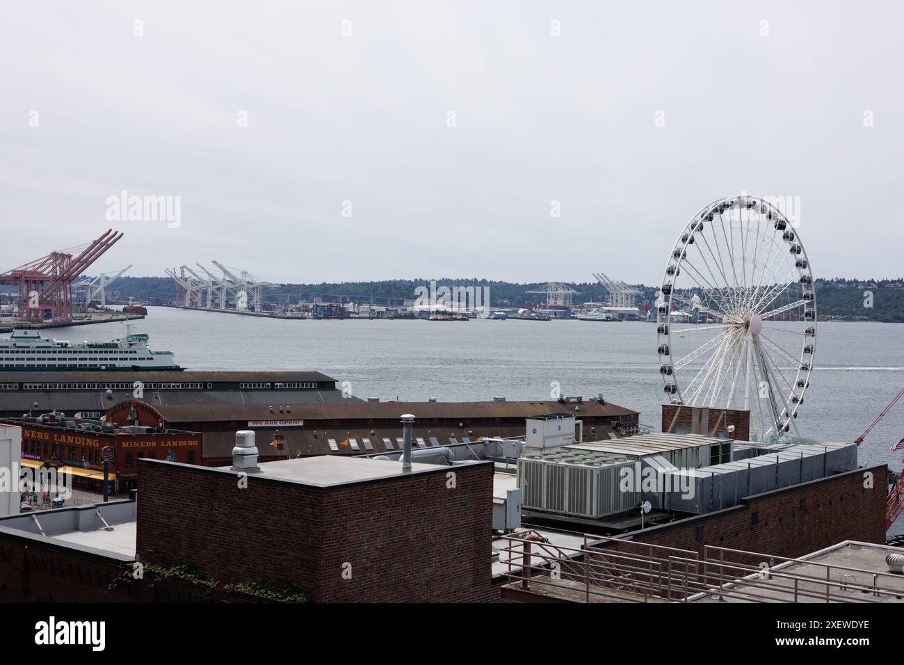 Seattle waterfront with ferris wheel, port cranes, and ferry in view ...