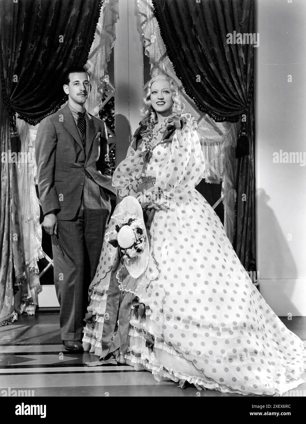 Costume Designer GILBERT ADRIAN and MARION DAVIES on set candid portrait during filming of ...