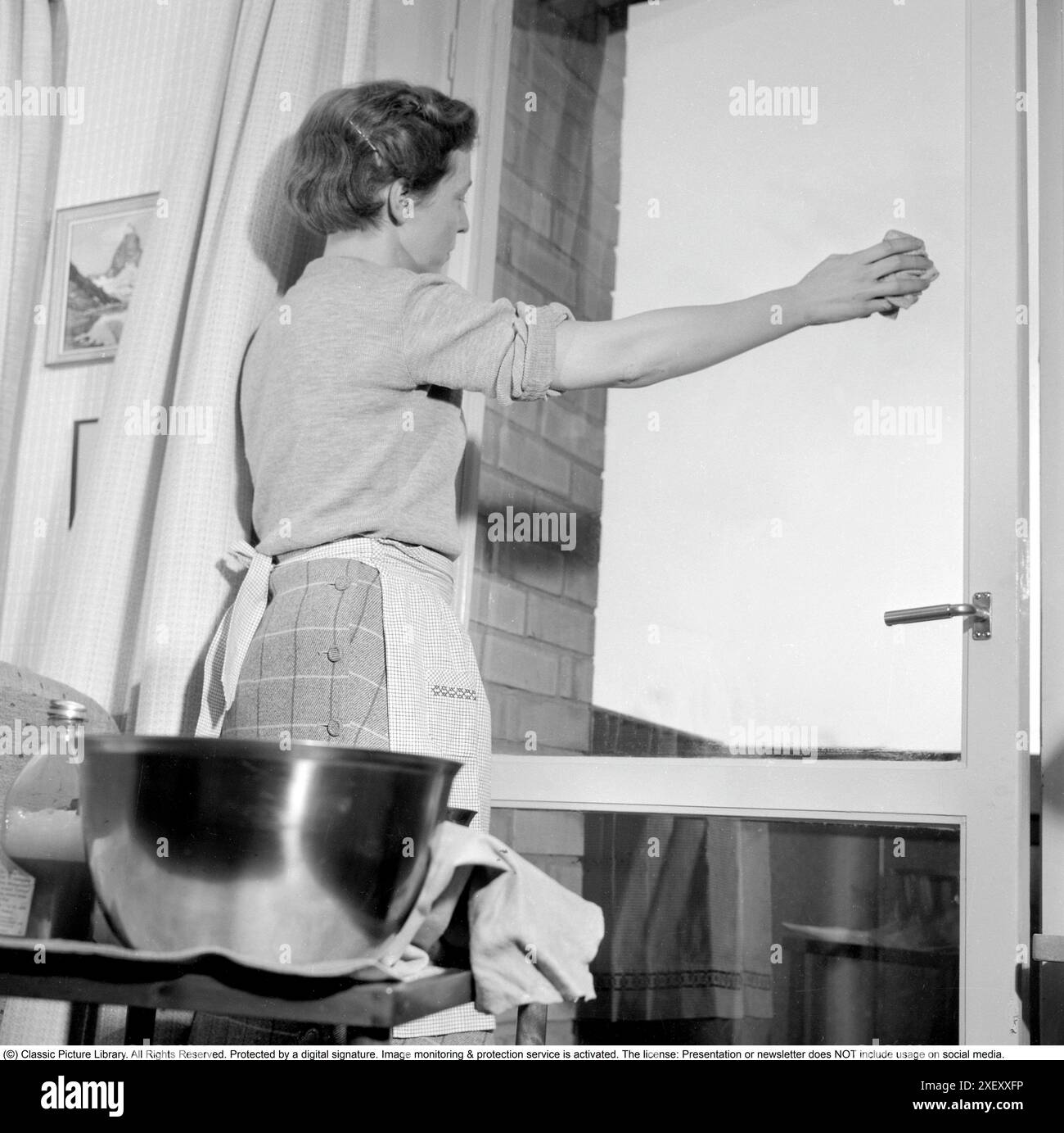 Windowcleaning in the 1950s. A woman is seen cleaning the windows of ...