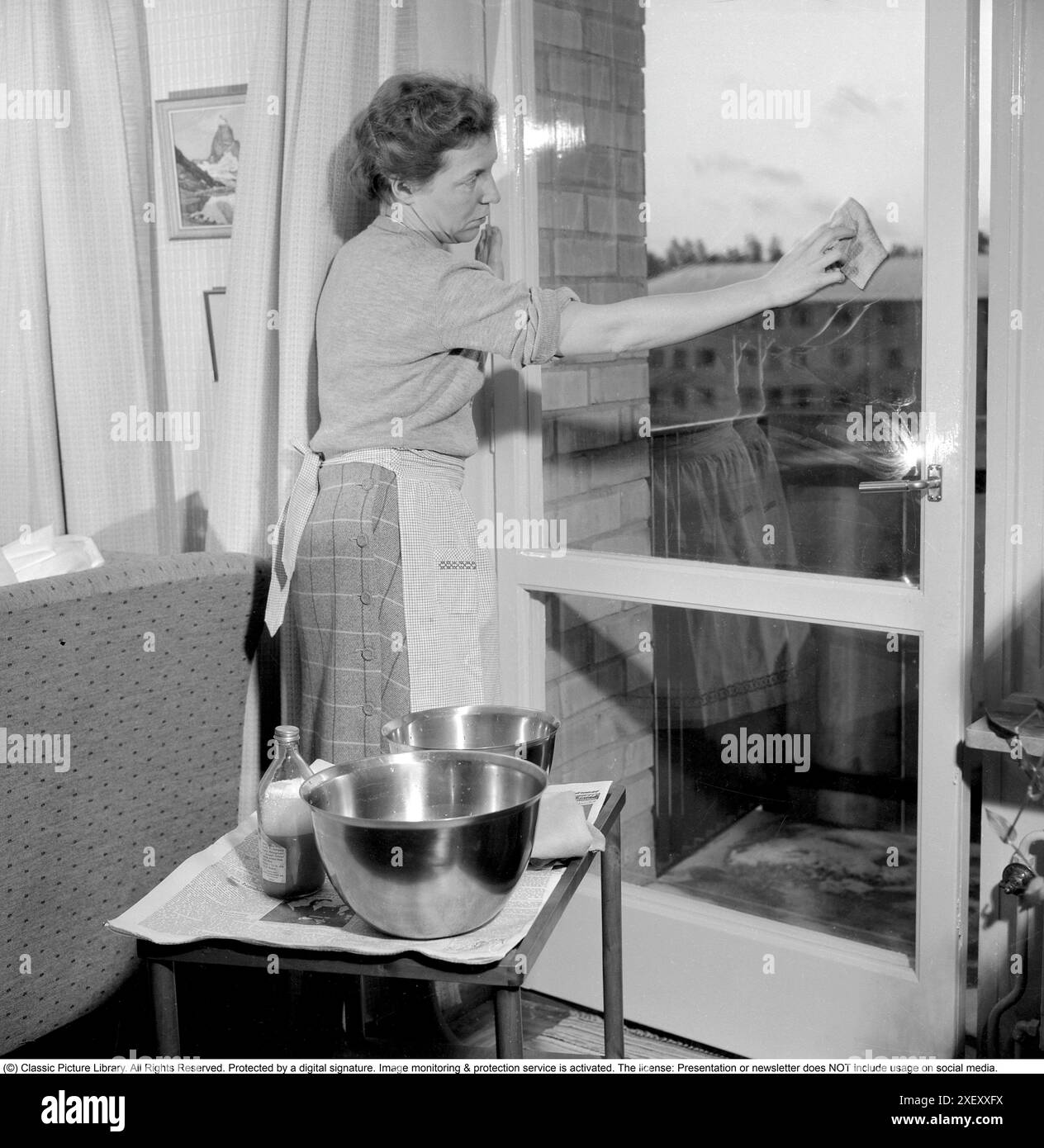 Windowcleaning in the 1950s. A woman is seen cleaning the windows of ...