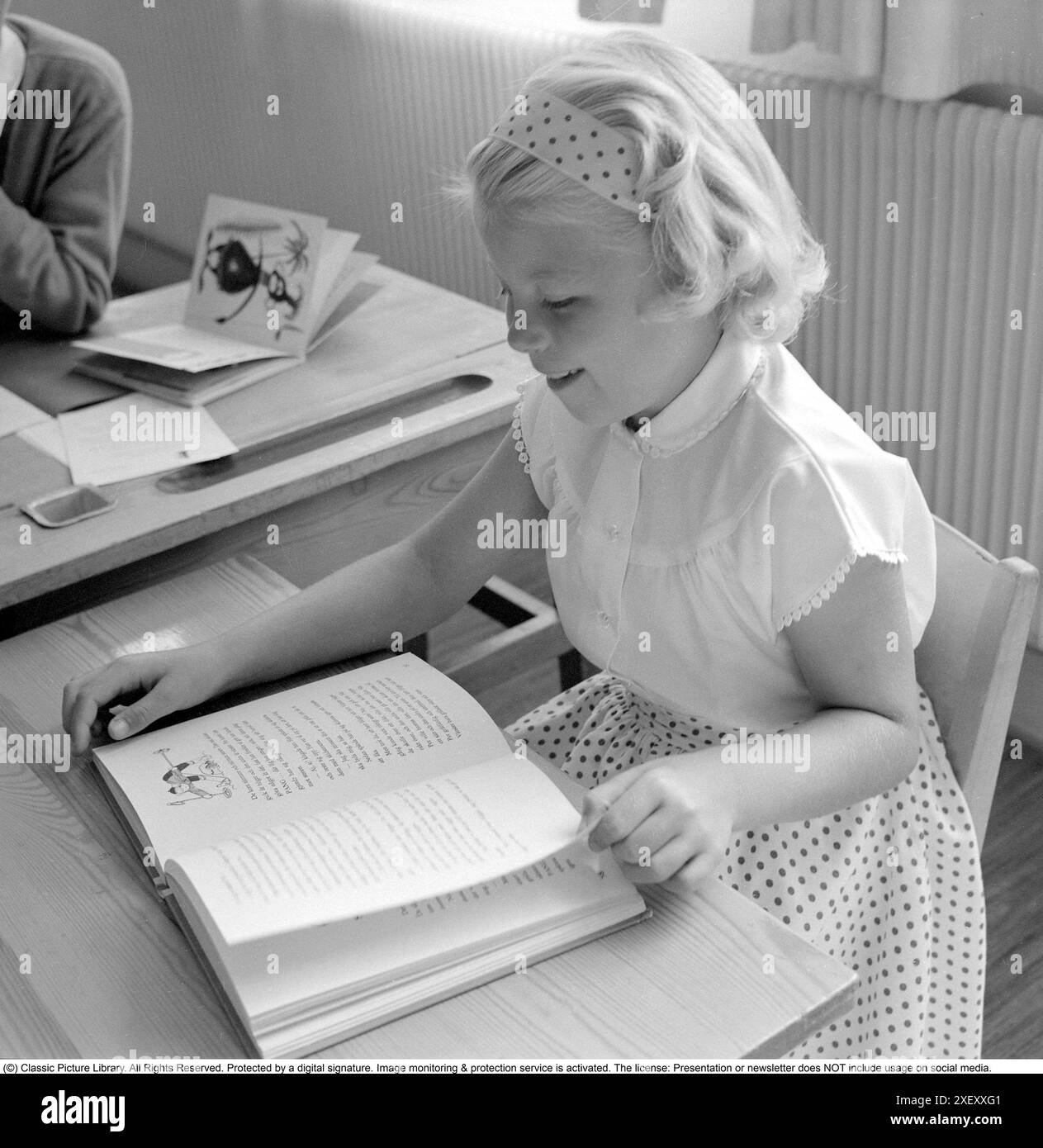 School in the 1950s. A girl is seen sitting at her desk in the ...