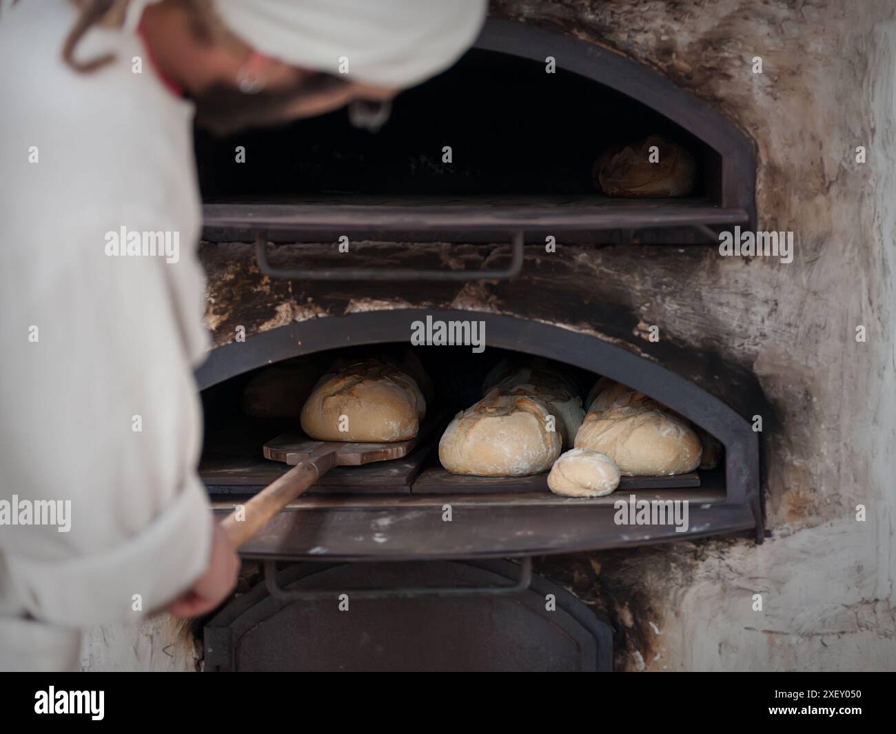 introducing mass baker of bread in wood stove Stock Photo - Alamy