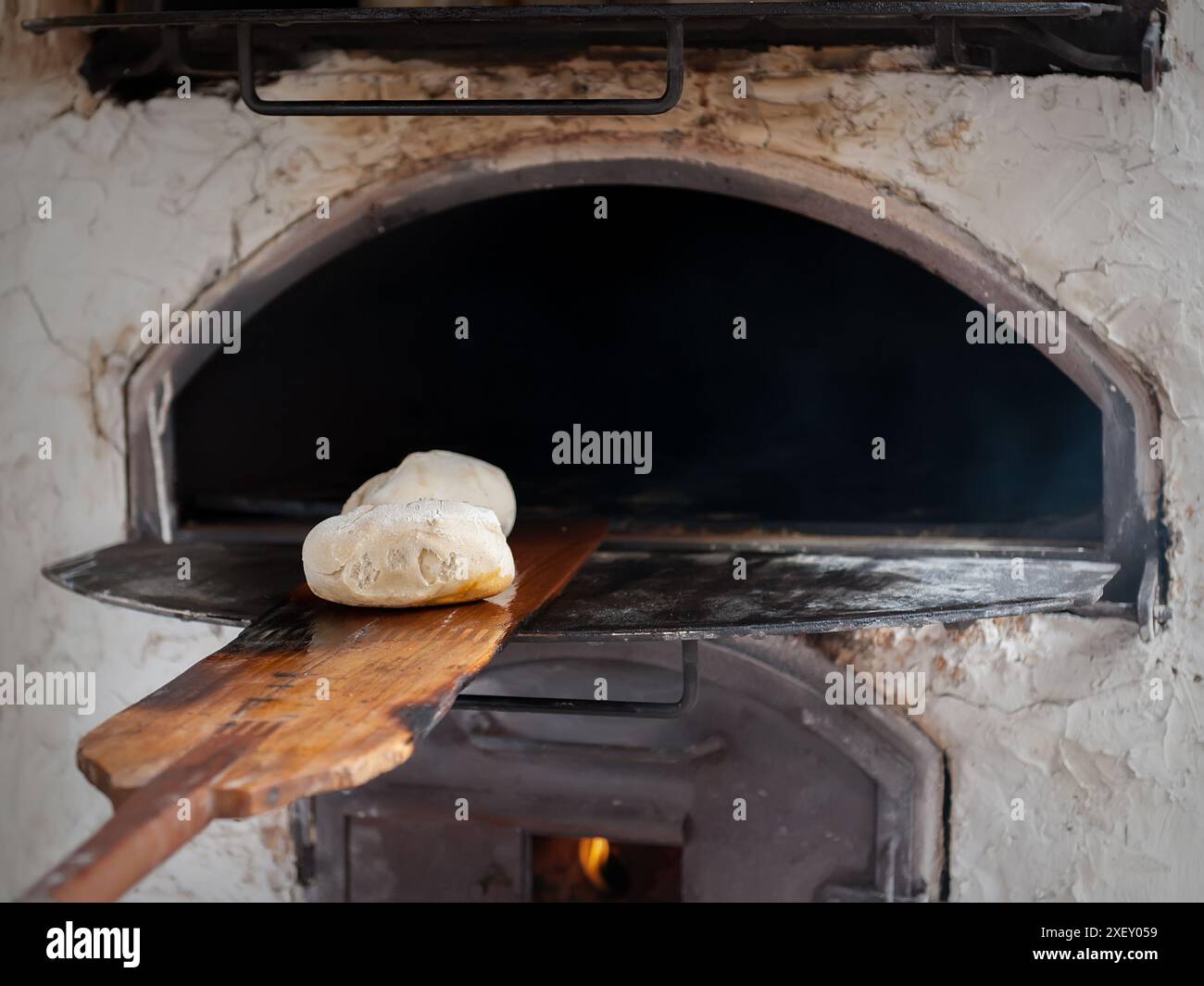 introducing mass baker of bread in wood stove Stock Photo - Alamy
