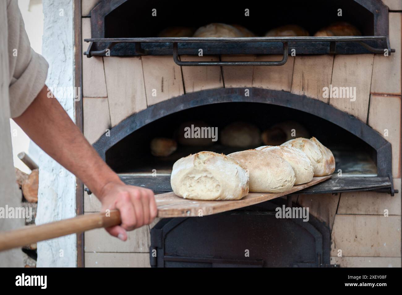 introducing baker bread dough in the oven of wood Stock Photo - Alamy