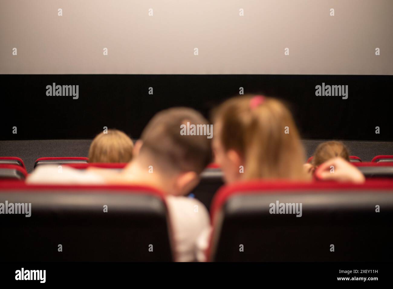 moviegoers sit in red chairs before the premiere of the film. family ...