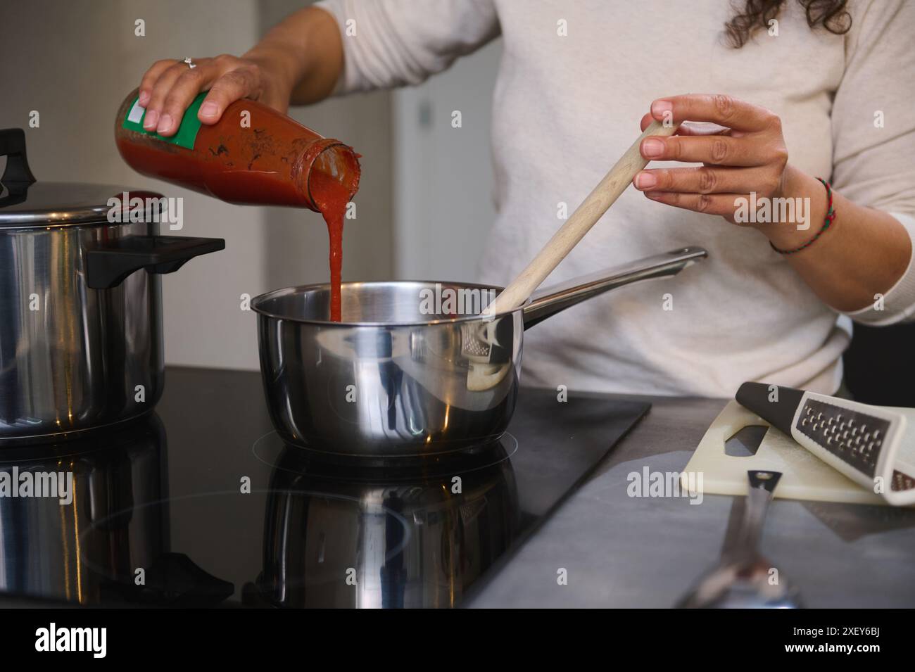 Close-up female chef's hands holding a wooden kitchen spoon and mixing ...