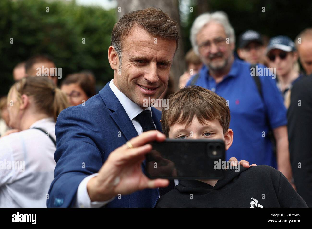 French President Emmanuel Macron takes a selfie with a boy after voting ...