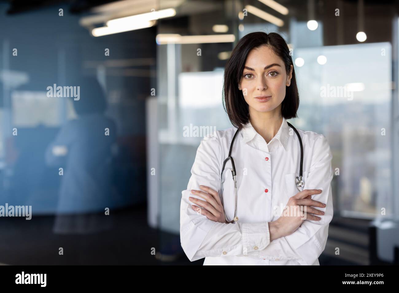 Confident female doctor with stethoscope standing in modern hospital ...