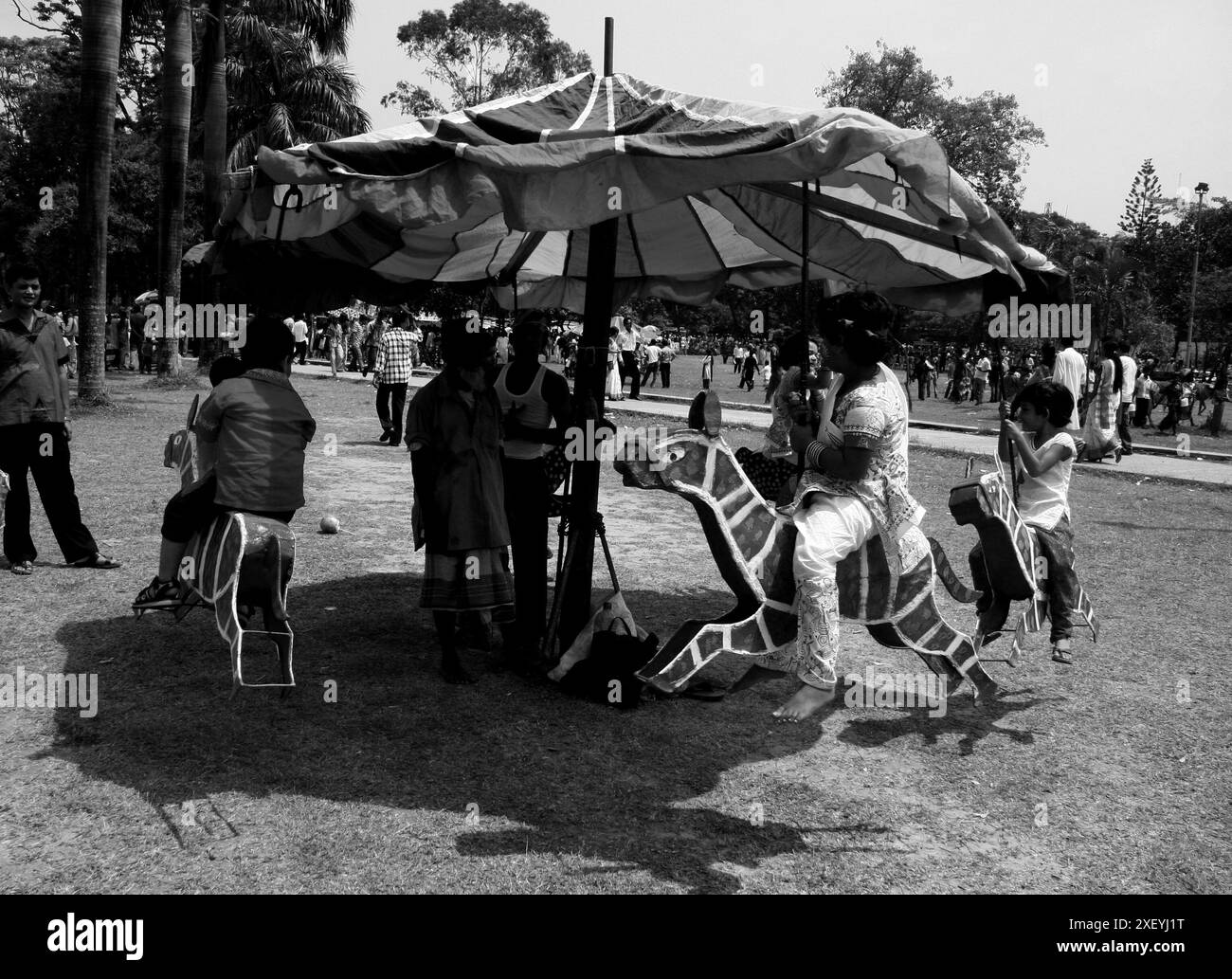 Children enjoy riding merry-go-round at a ground in front of Dhaka ...