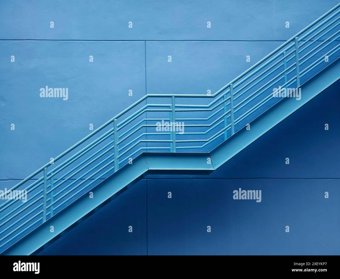 A set of stairs ascending a large blue wall Stock Photo - Alamy