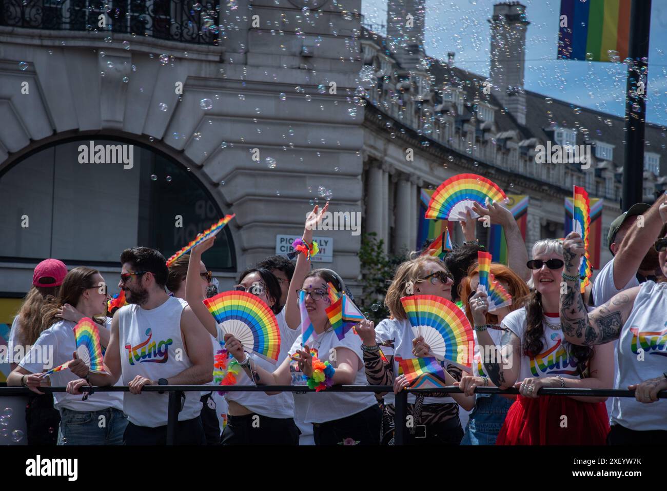 London, UK. 29th June, 2024. Party revellers dance with rainbow fans ...
