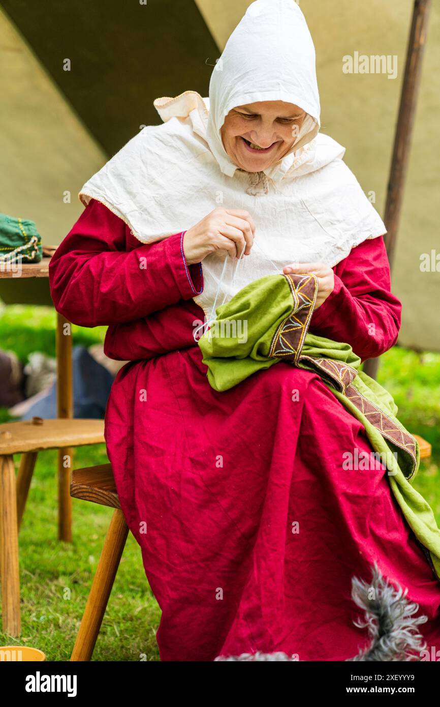 Senior women in medieval costume sitting sawing a garment. Wearing ...