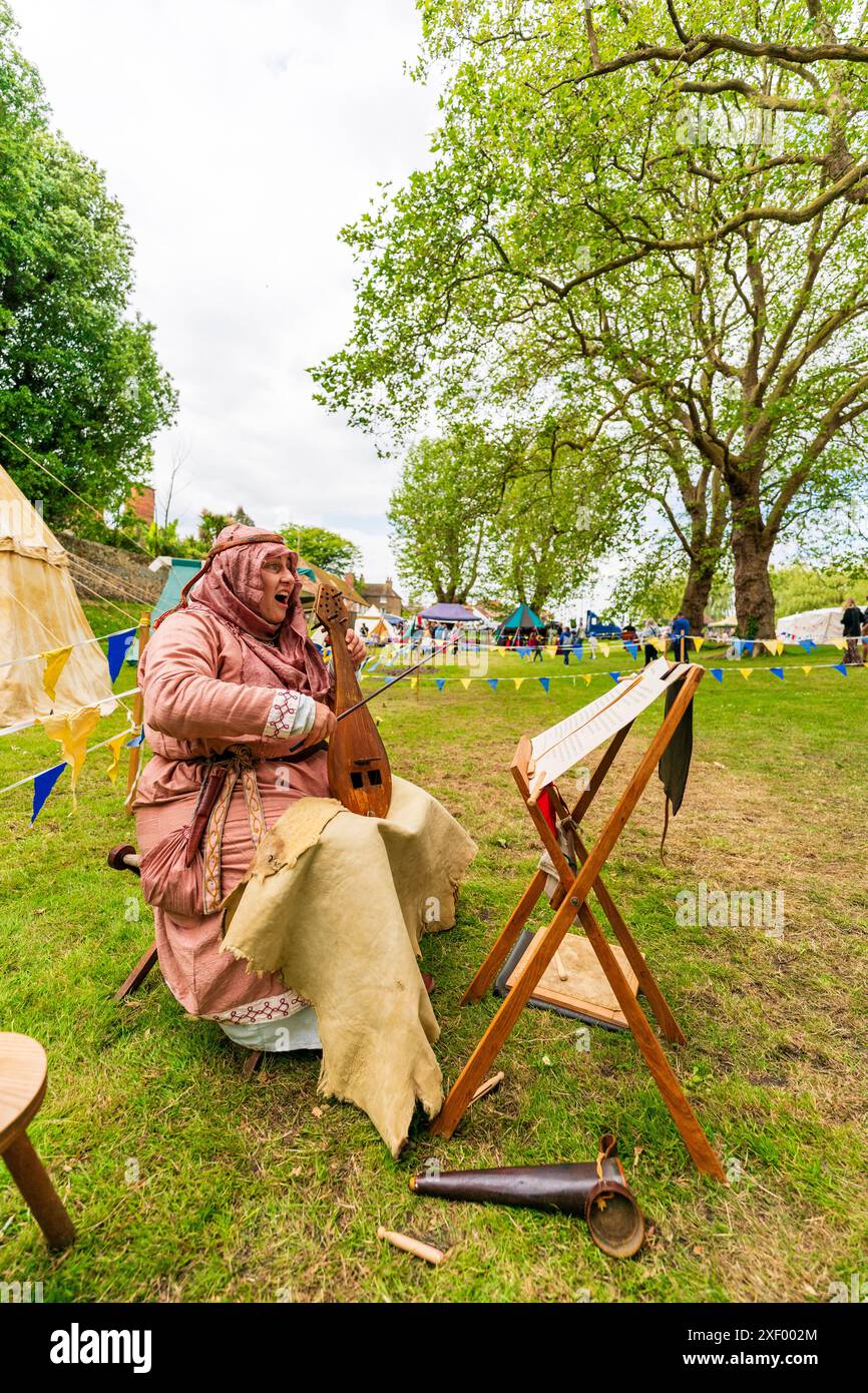 Close up of a woman dressed in medieval costume singing and playing a ...