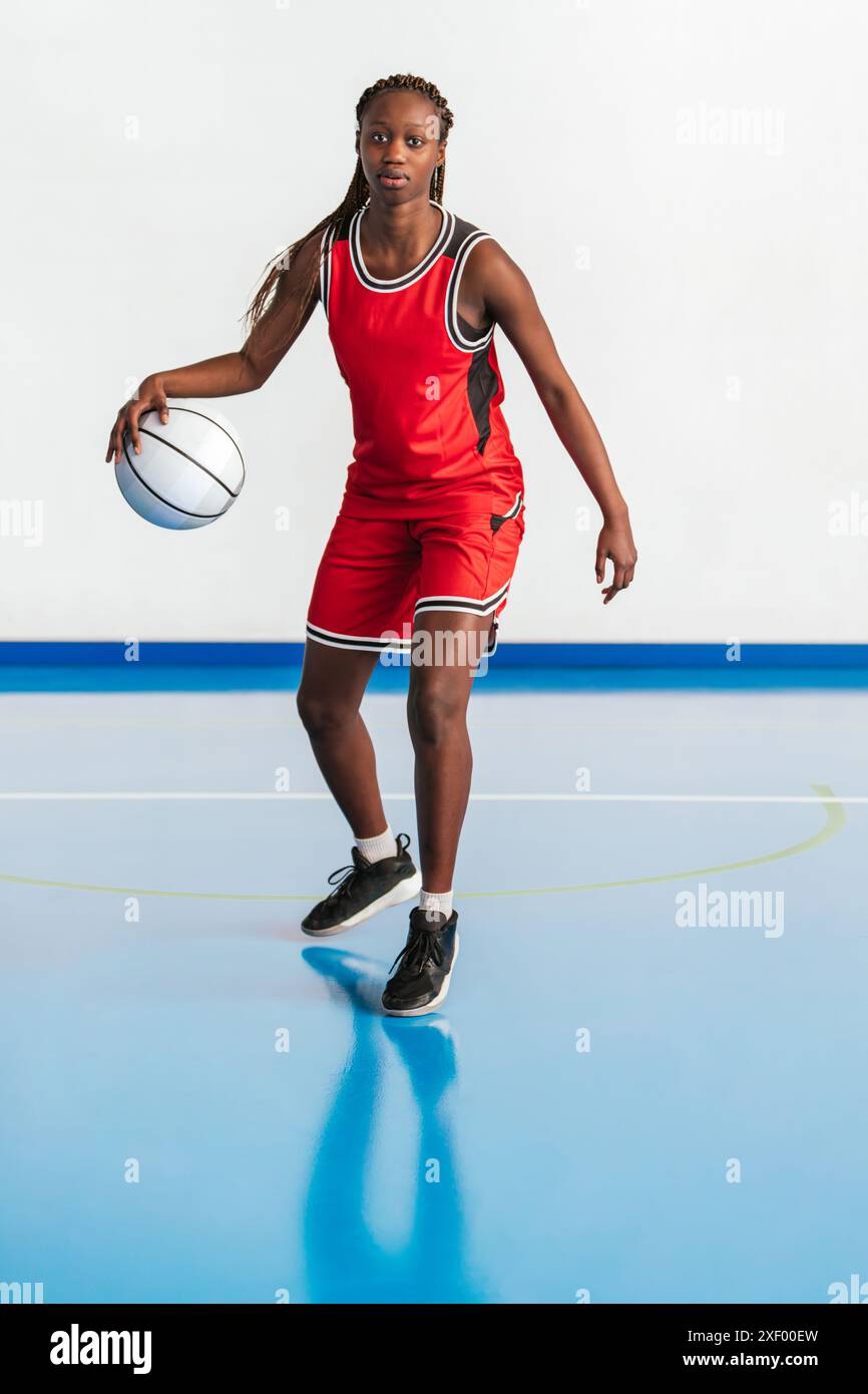 Vertical photo a female basketball player in a red uniform practices ...