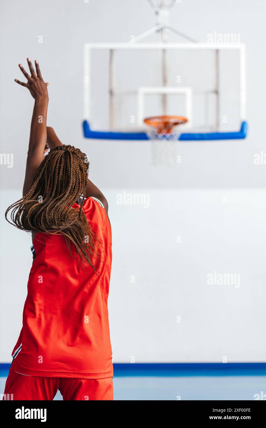 Vertical photo a female basketball player in a red uniform executes a ...