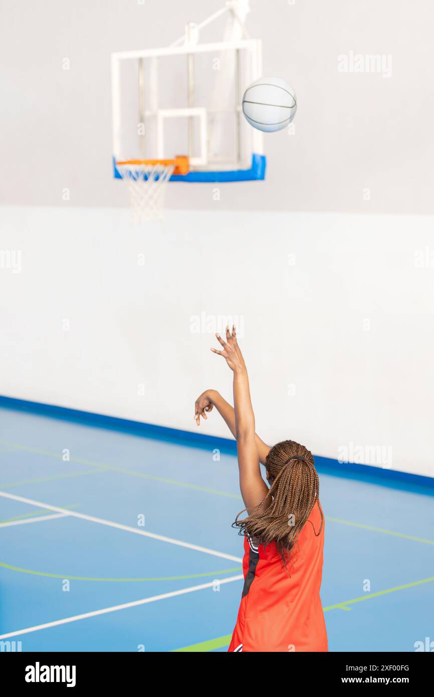 Vertical photo a female basketball player in a red uniform executes a ...