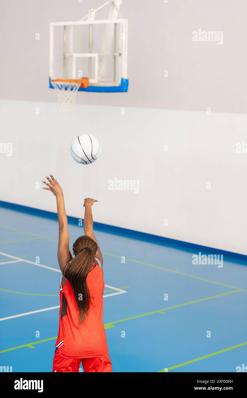 Vertical photo a female basketball player in a red uniform executes a ...
