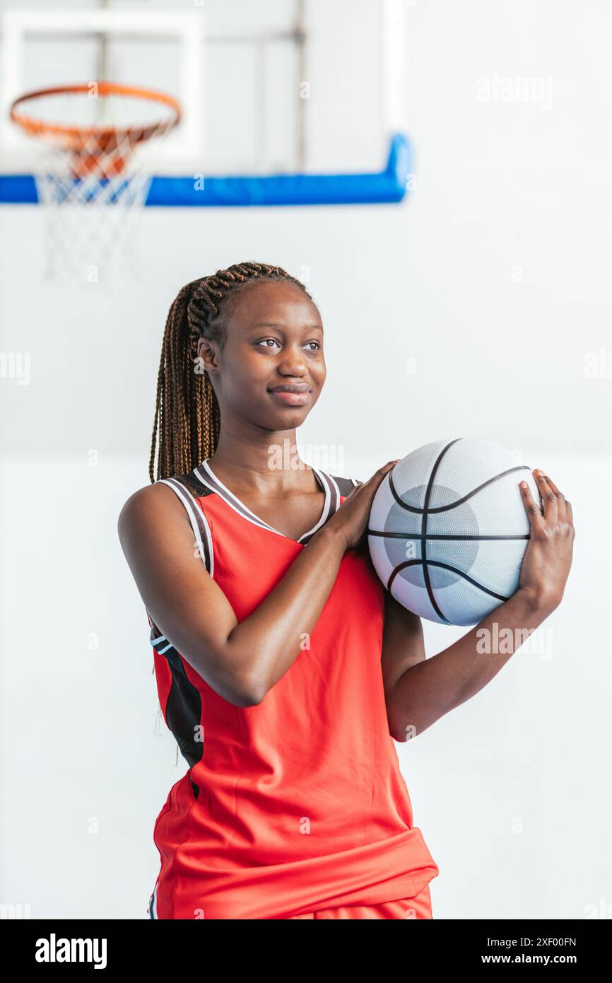 Vertical photo young female basketball player in a red uniform holds a ...