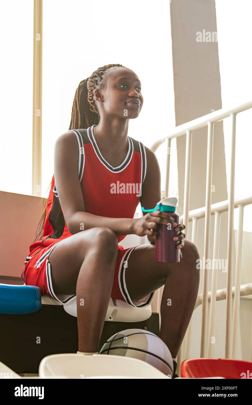 Vertical photo young female basketball player in a red jersey sitting ...
