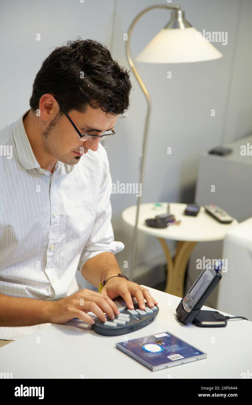 Person labeling a music CD using the braille BlueType keyboard The ...