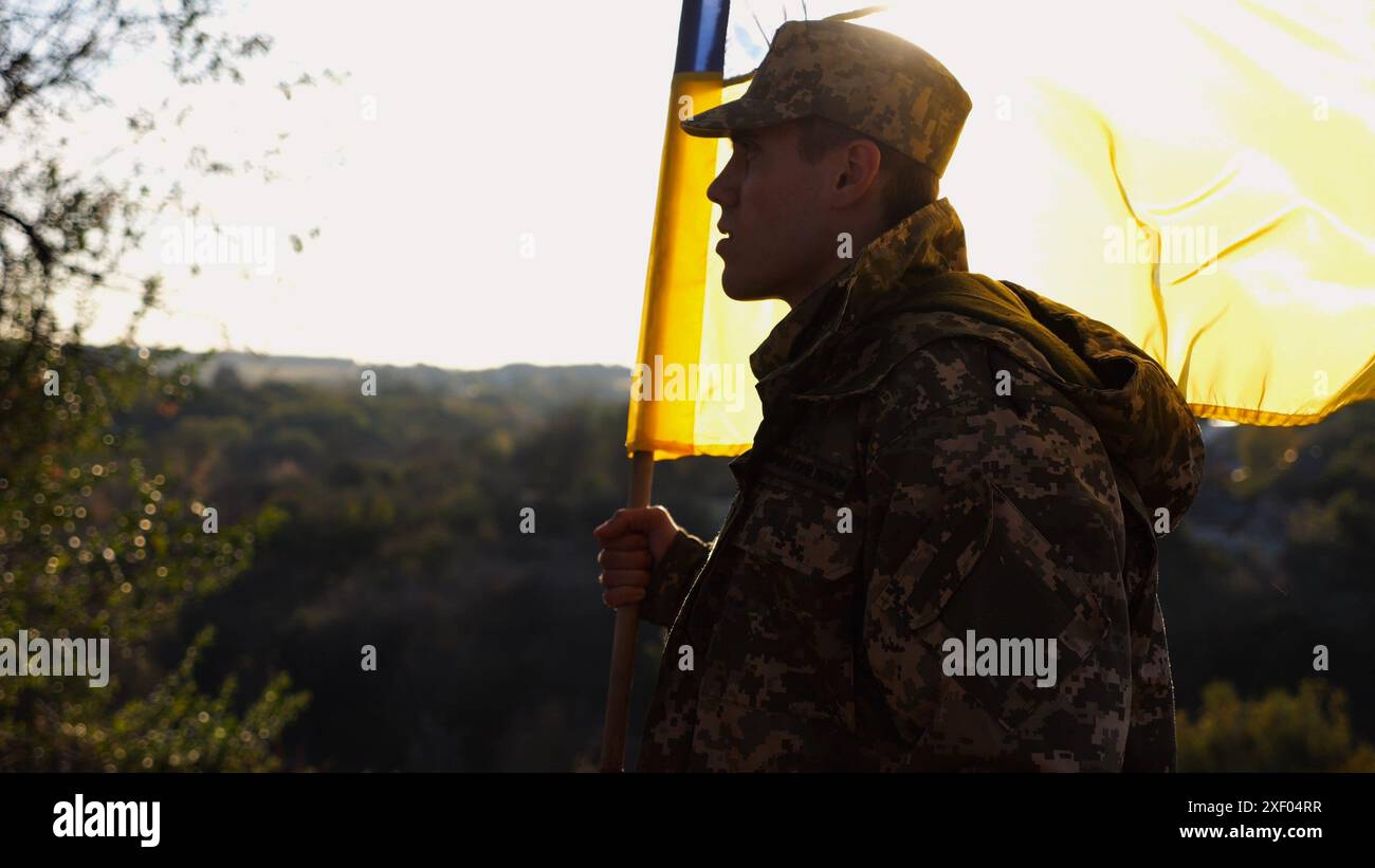 Soldier of ukrainian army stands with lifting blue-yellow banner at ...