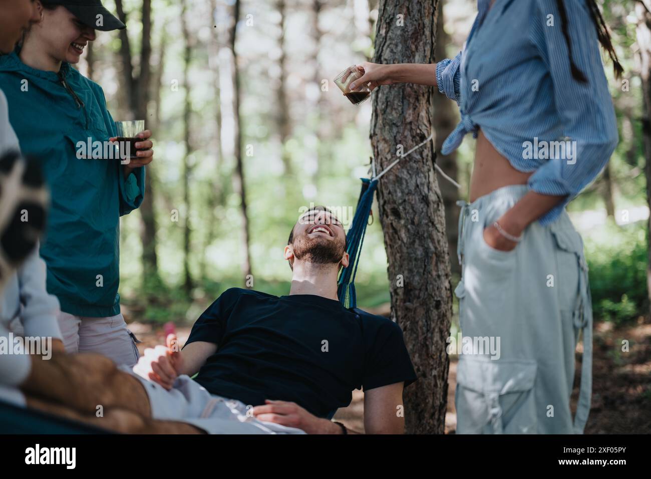 Friends enjoying a casual outdoor hangout in the forest with drinks and ...