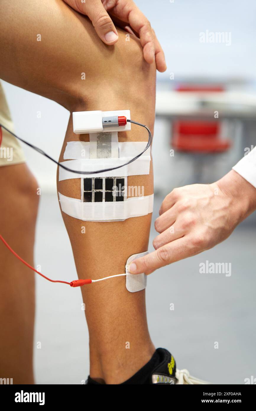 Researcher placing multipad electrodes in the leg to control ...