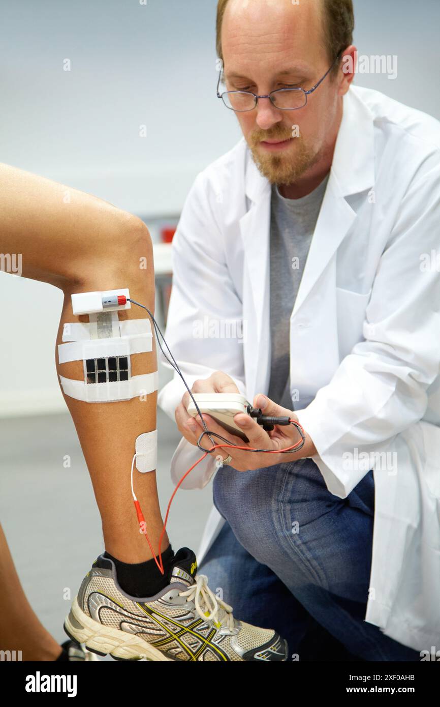 Researcher placing multipad electrodes in the leg to control ...
