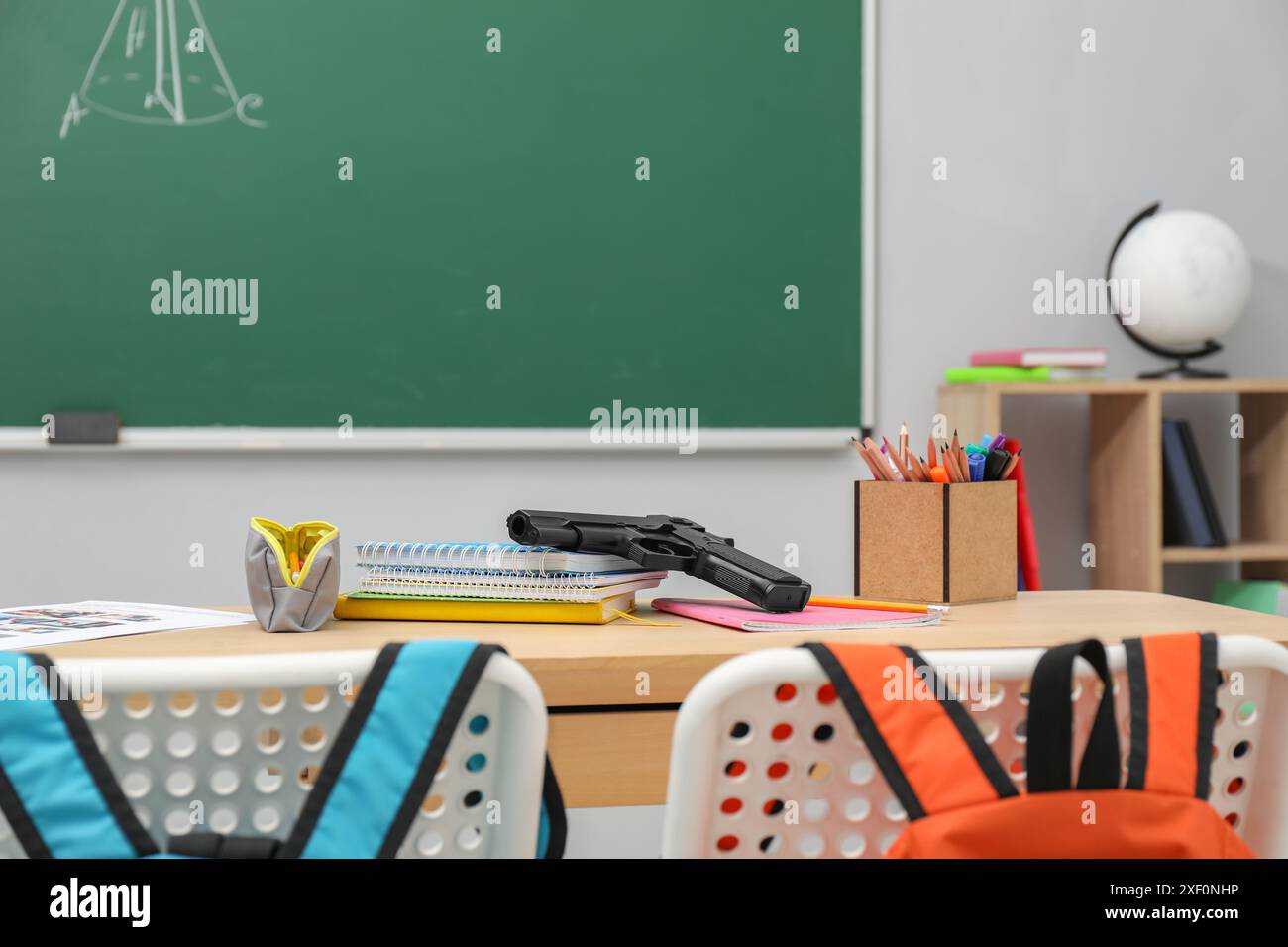 School stationery and gun on desk in classroom Stock Photo - Alamy