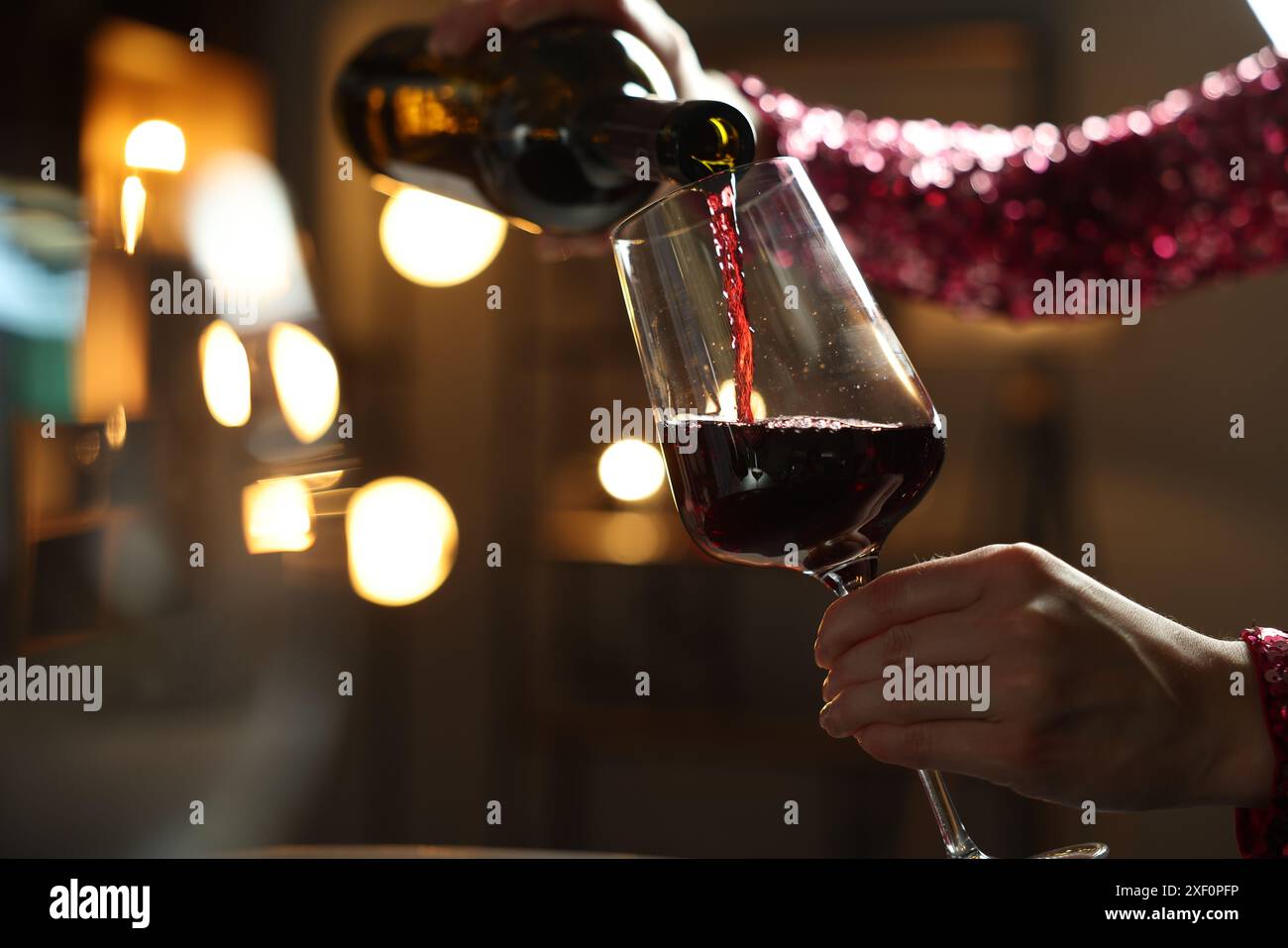 Woman pouring red wine from bottle into glass on blurred background ...