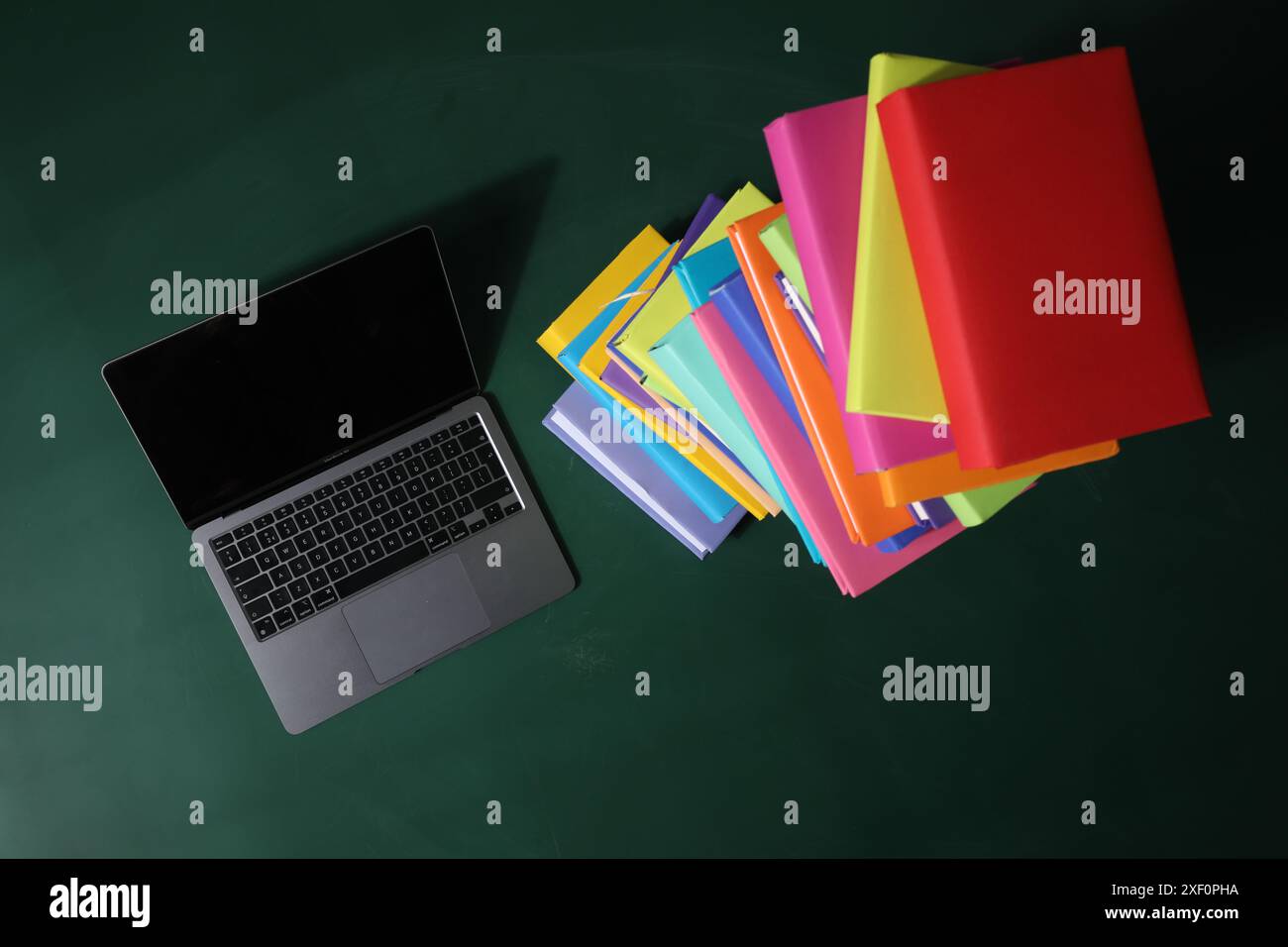 Stack of many colorful books and laptop on green background, flat lay ...