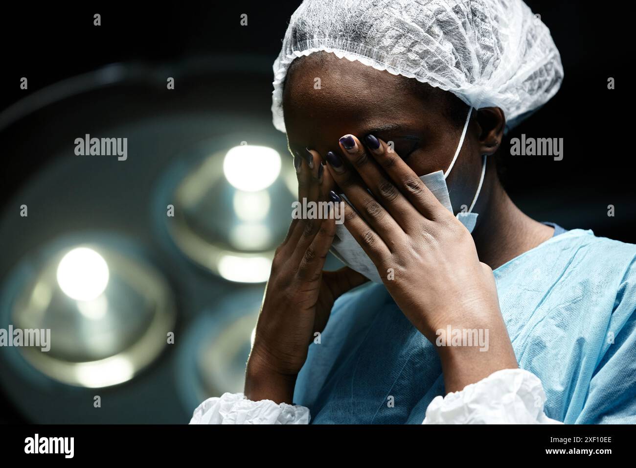 Dramatic portrait of young Black woman as tired female surgeon rubbing ...