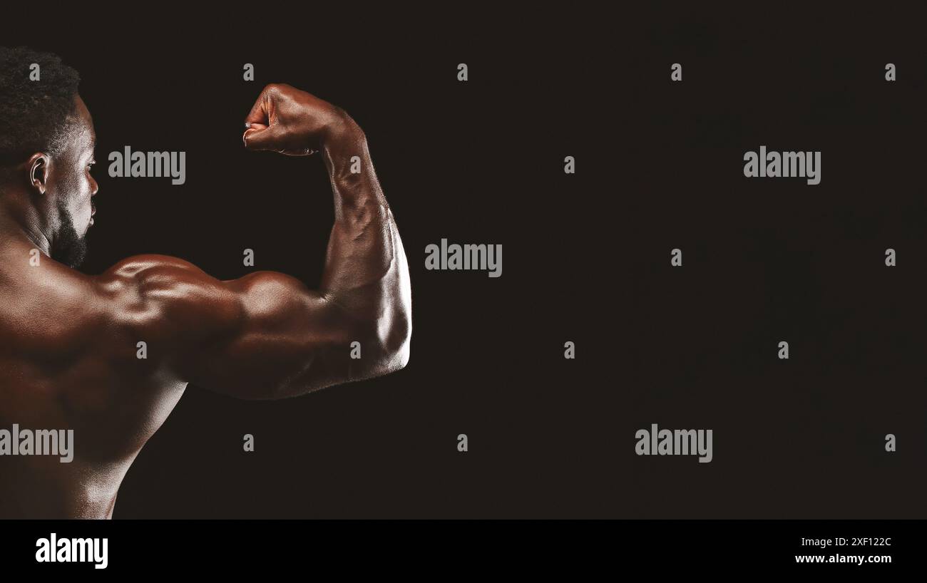 Muscular Man Flexing Bicep Against Black Background Stock Photo - Alamy