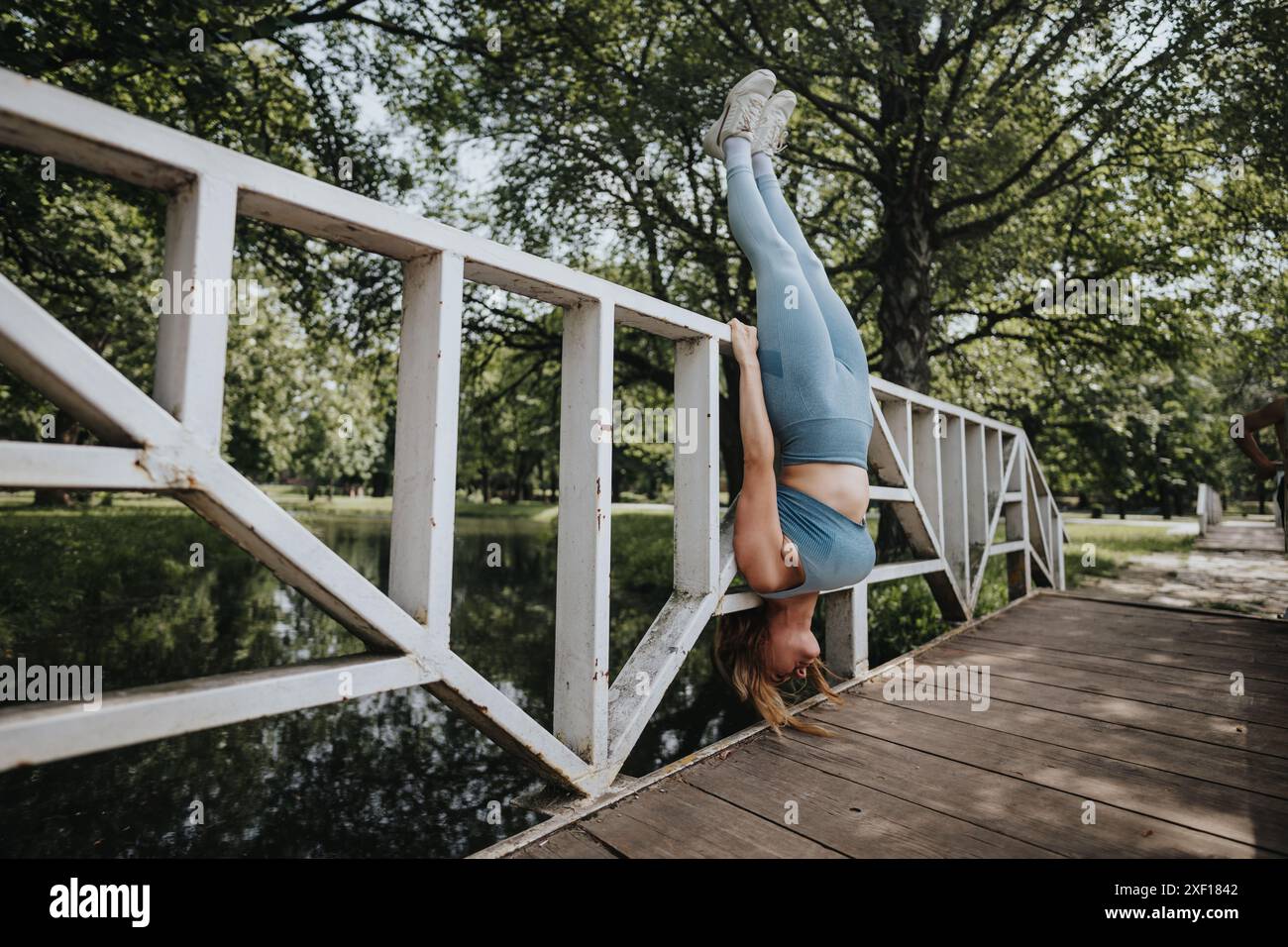 Woman performing handstand on bridge in a park during a sunny day Stock ...