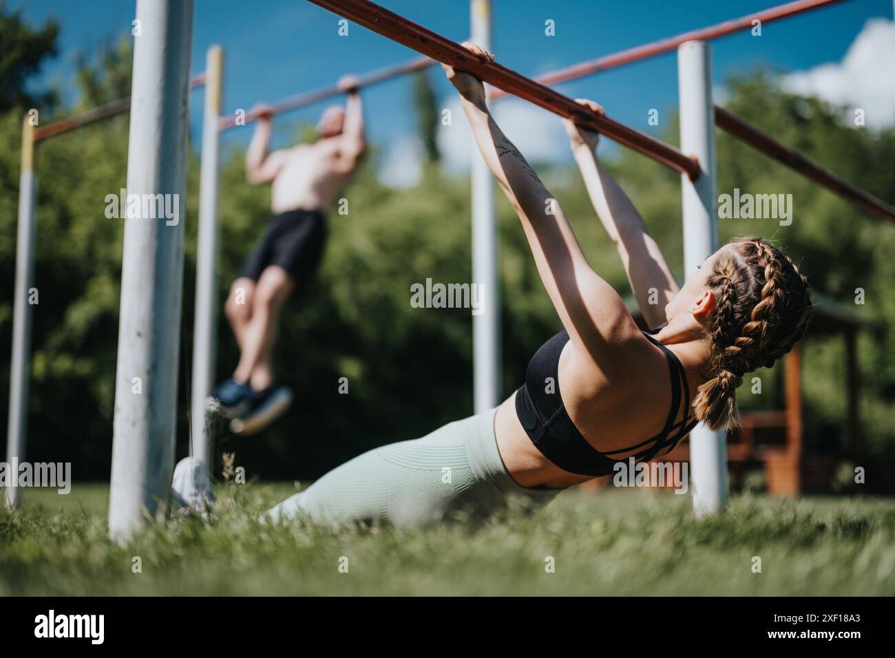 Man and woman doing outdoor workouts on fitness bars in park Stock ...