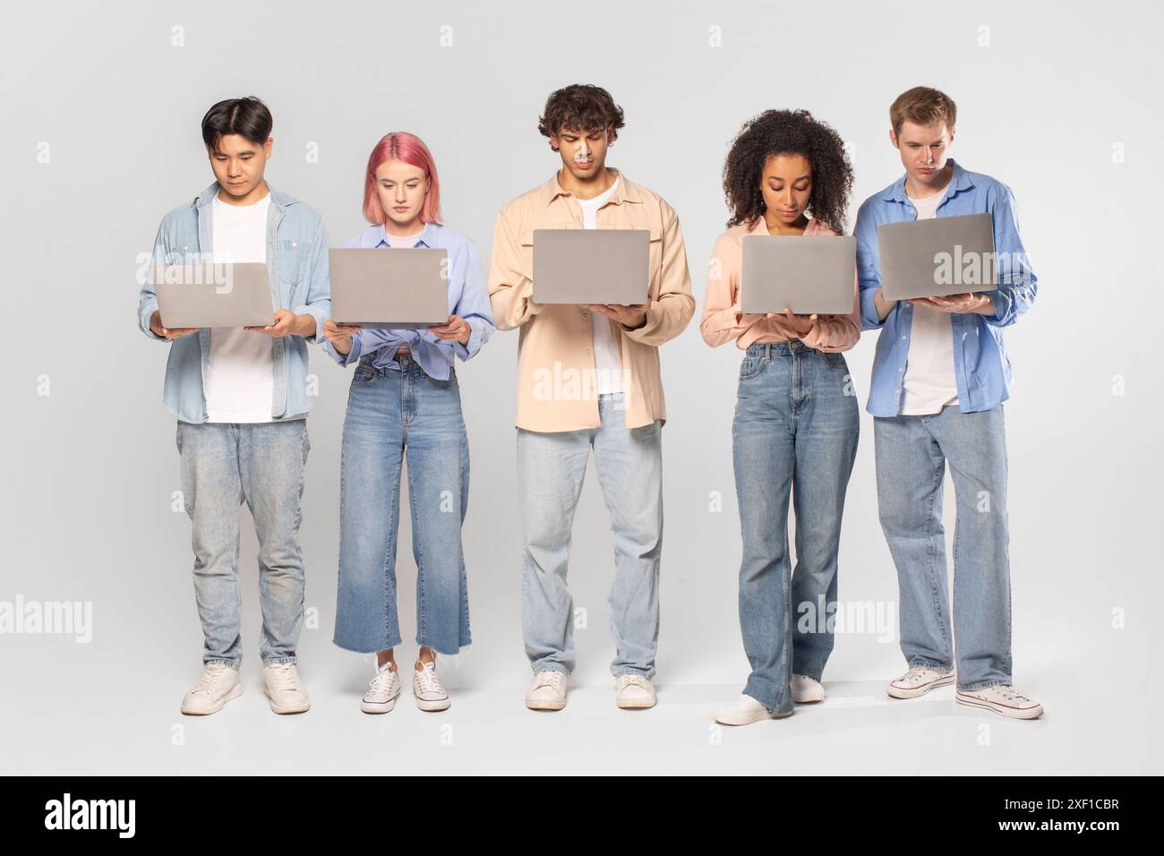 Five Diverse Young Adults Using Laptops in Studio Setting Stock Photo ...
