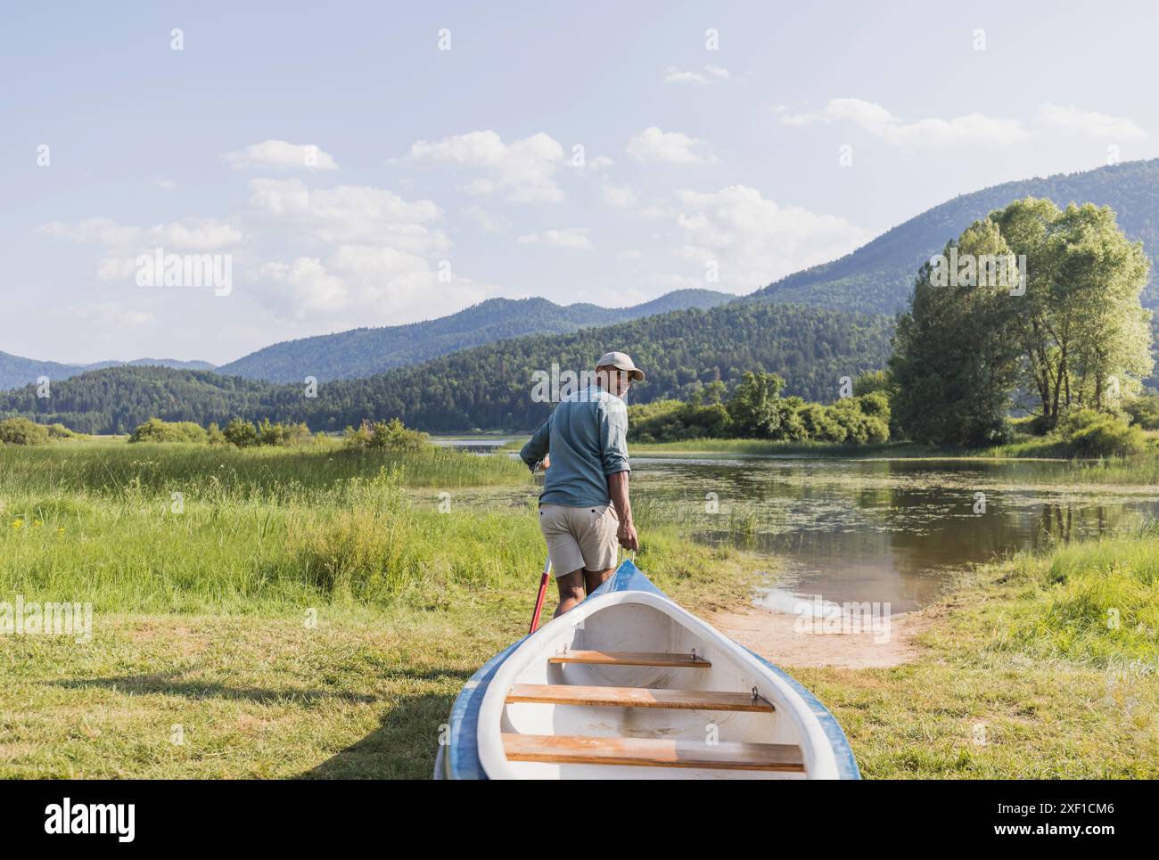 Young man pulling a canoe into the water on the beautiful lakeshore ...