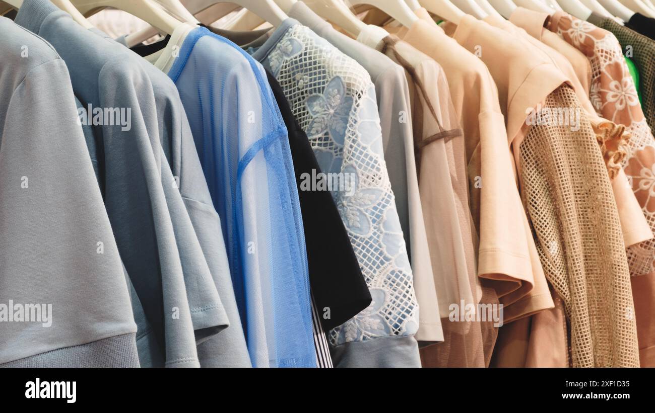A row of clothes hanging on a rack, including a blue shirt with a white ...